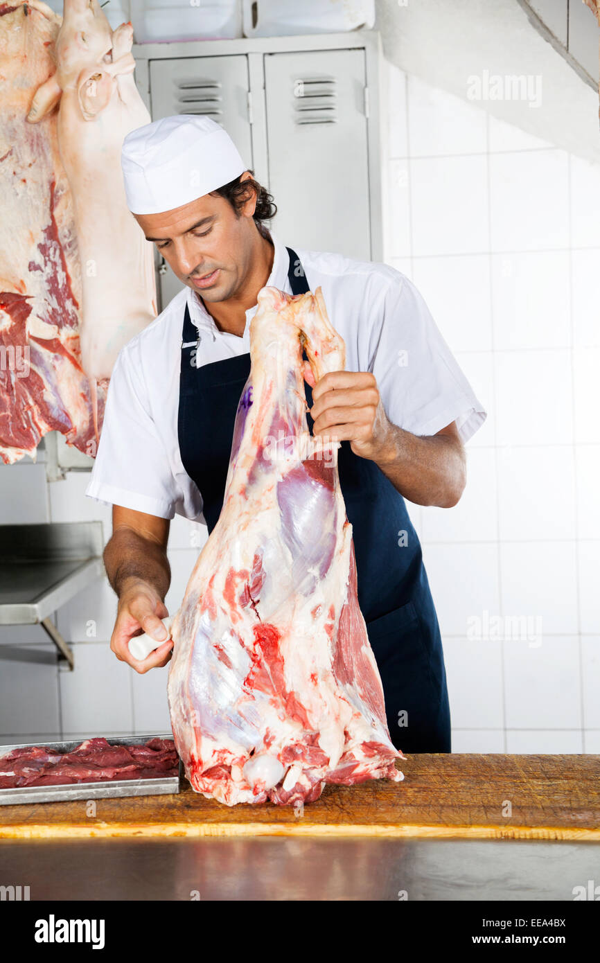 Butcher With Meat Working At Counter Stock Photo - Alamy