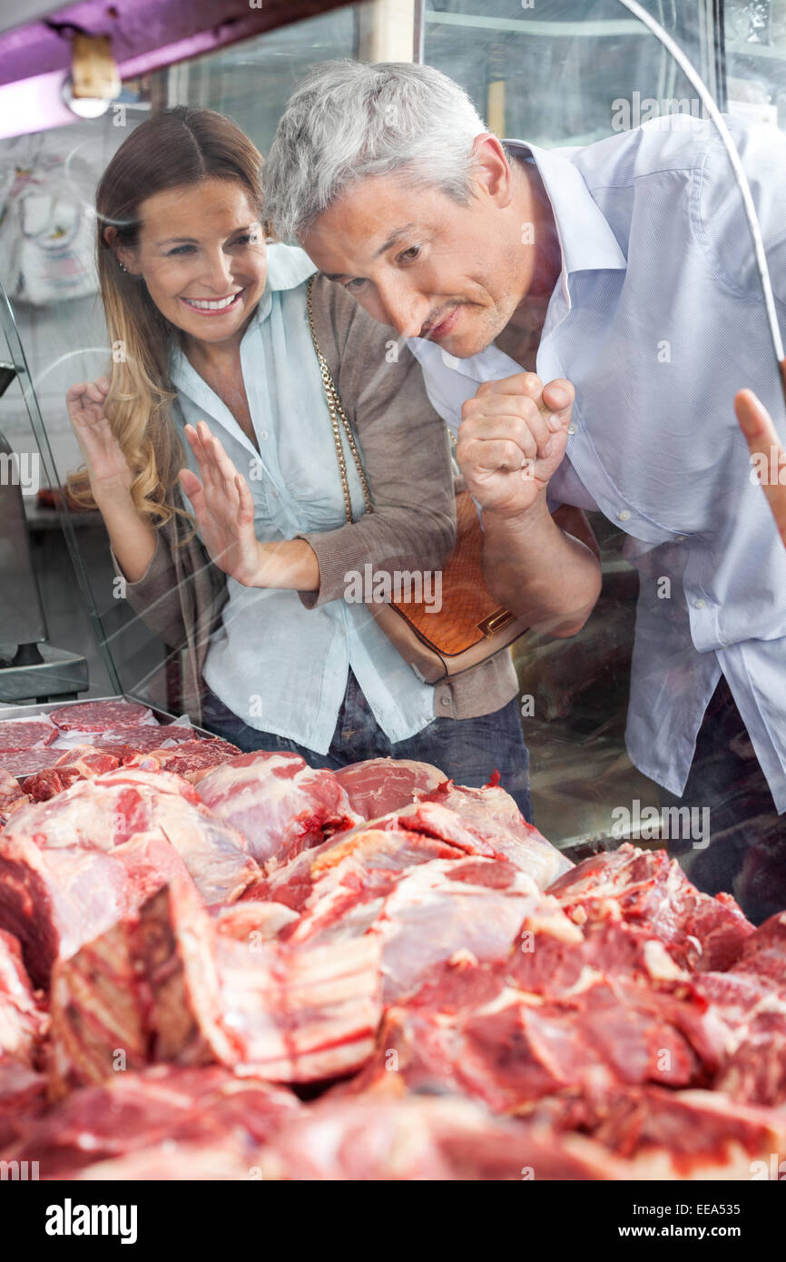 Couple Looking At Meat Through Cabinet In Butchery Stock Photo - Alamy