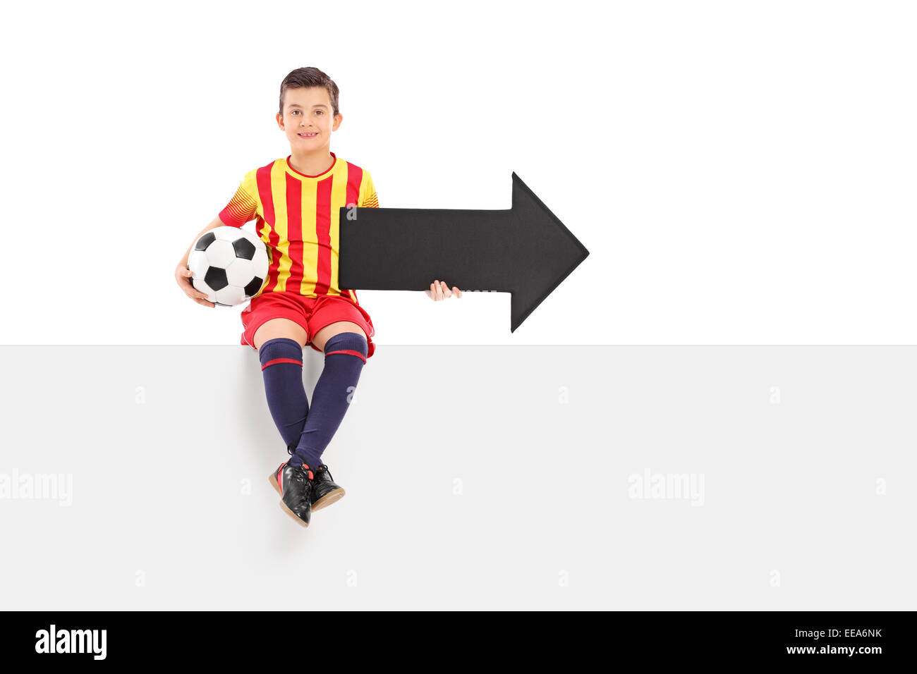 Junior athlete holding an arrow and a football seated on a bank ...