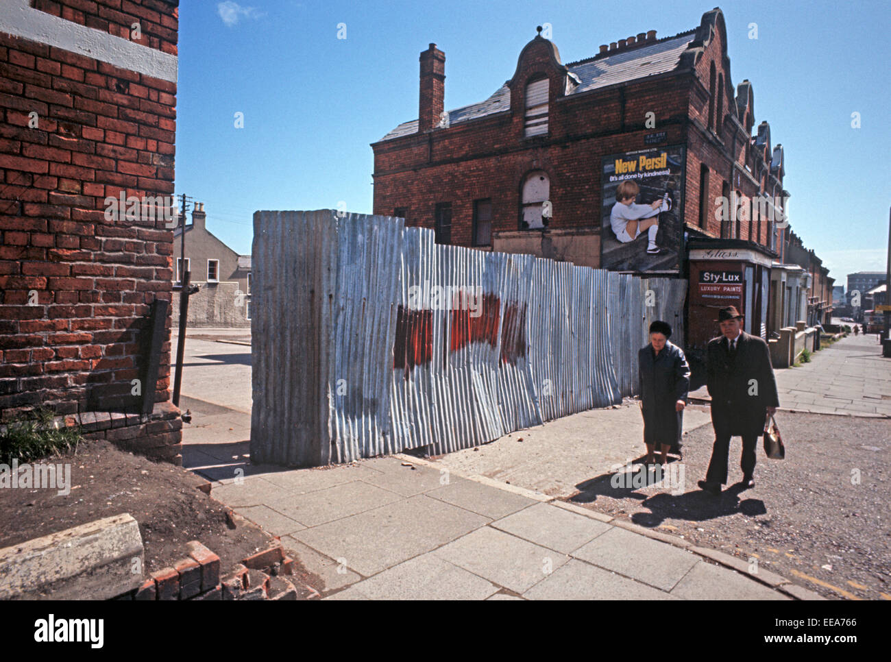 BELFAST, NORTHERN IRELAND - MAY 1972. Couple walking past one of the ...