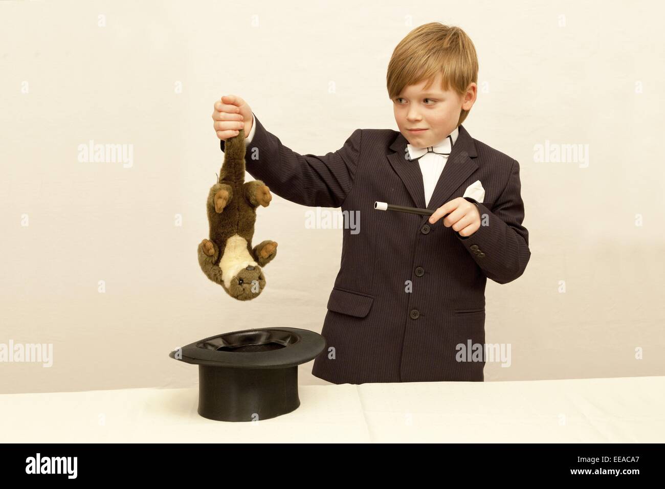 young boy dressed up as a magician pulling a soft toy from his top hat ...