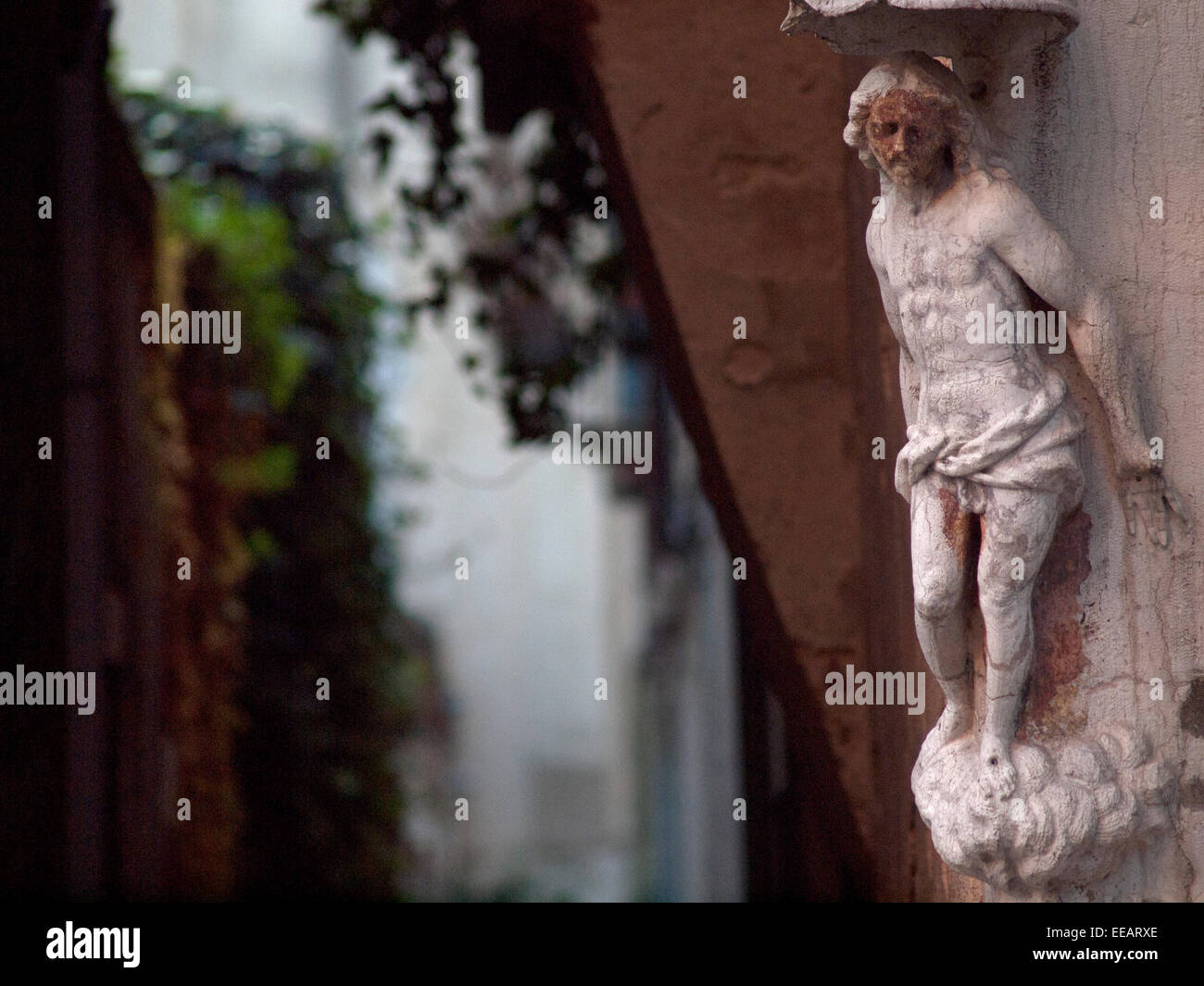 A statue of Jesus on the corner of a building in a back street of ...