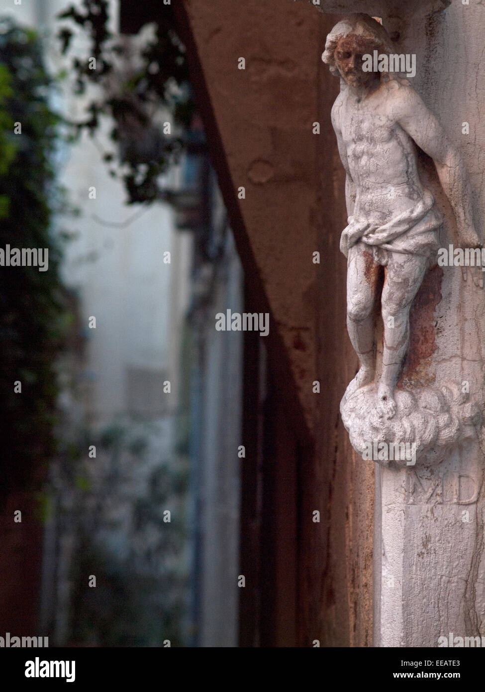 A statue of Jesus on the corner of a building in a back street of ...