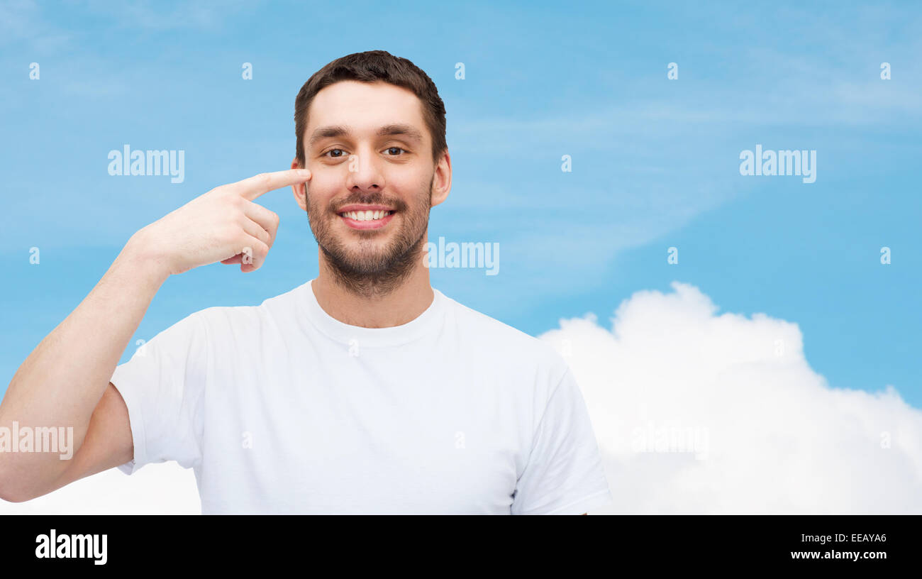 smiling young handsome man pointing to eyes Stock Photo - Alamy