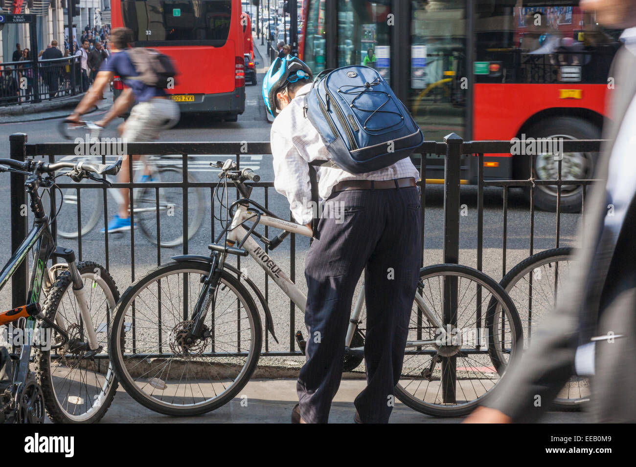 England, London, City of London, Cyclist Attaching Bicycle to Railings ...