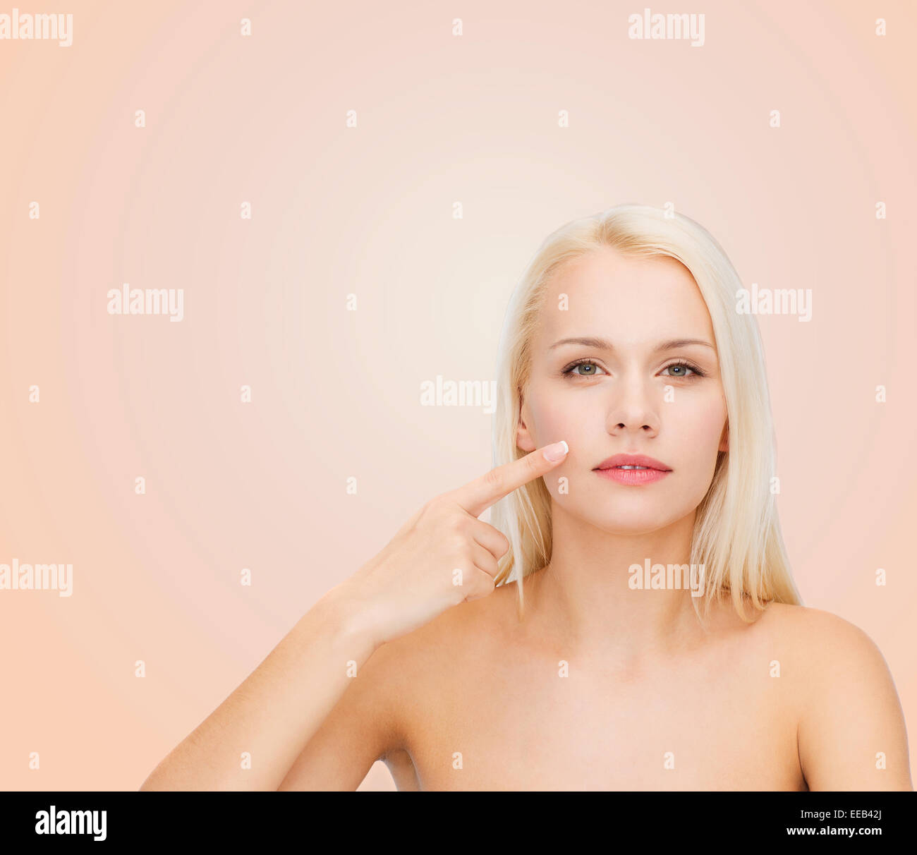 calm young woman pointing at her cheek Stock Photo - Alamy