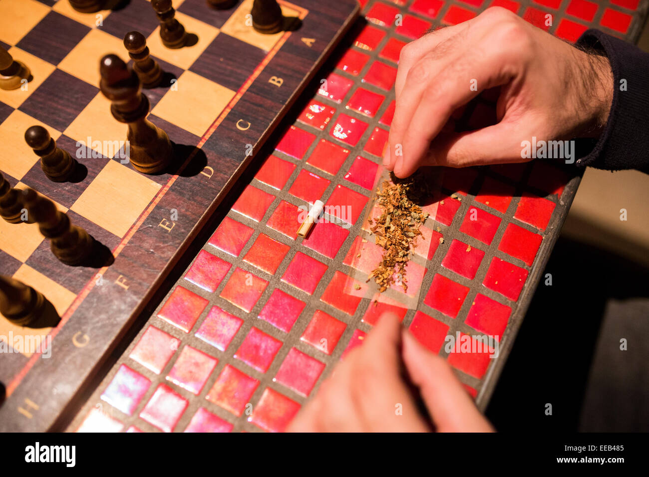 A customer rolls a marijuana cigarette in front of a chess board at the ...