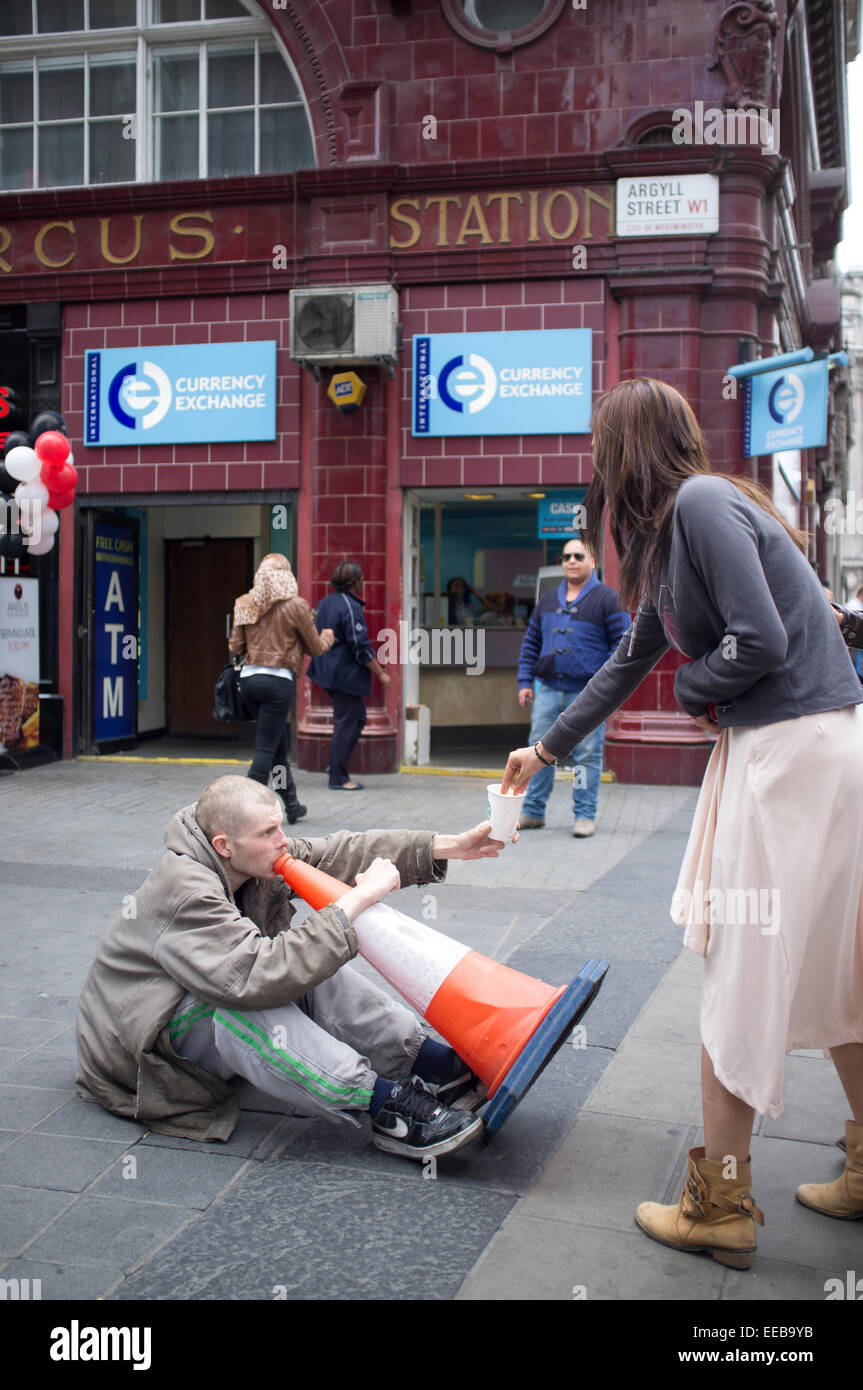 Homeless male playing music on a street cone outside Oxford Circus ...