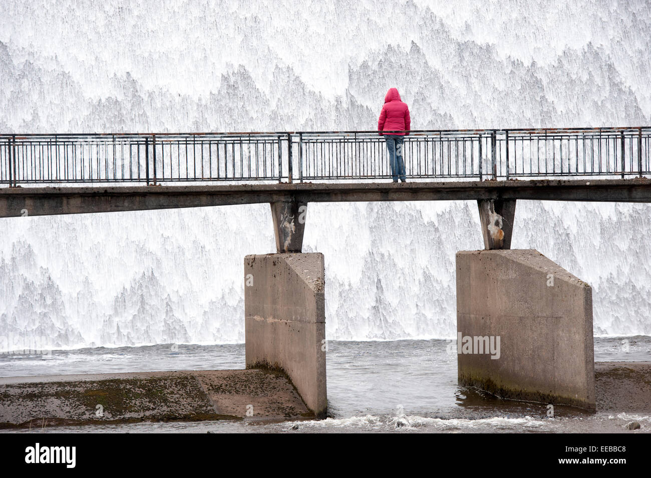 water cascading down reservoir overflow outlet, with person watching ...
