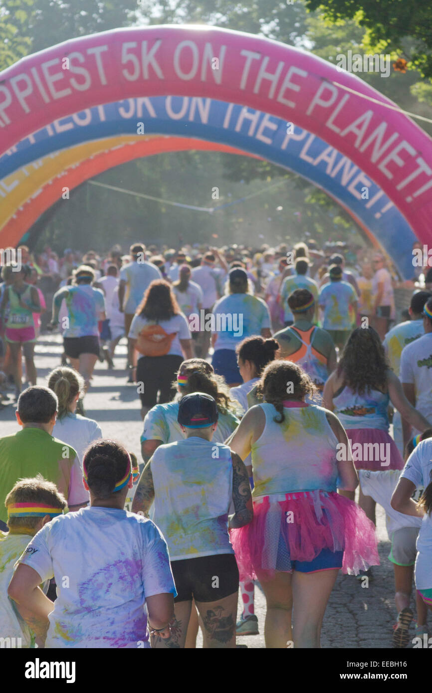 Runners splattered with colorful dyes approach the finish line in the ...