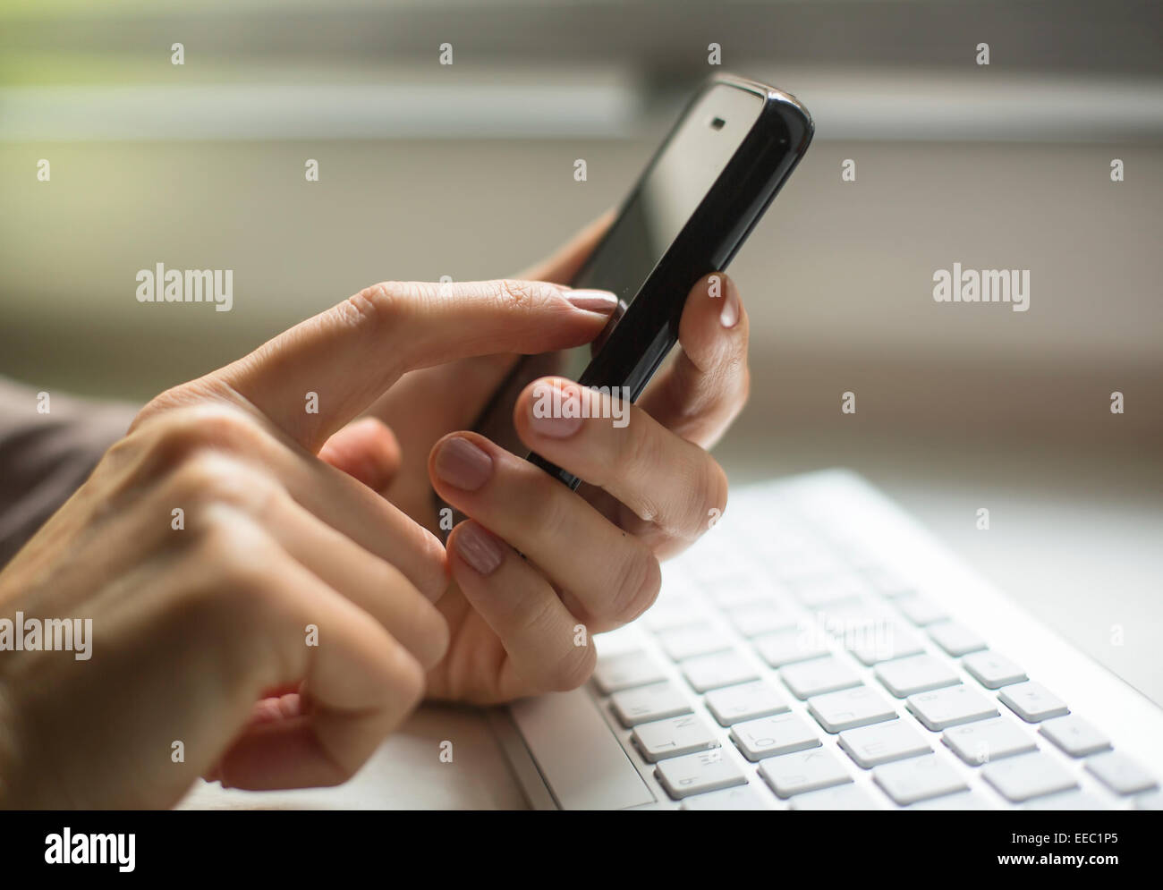 Smartphone and computer keyboard at hand Stock Photo - Alamy