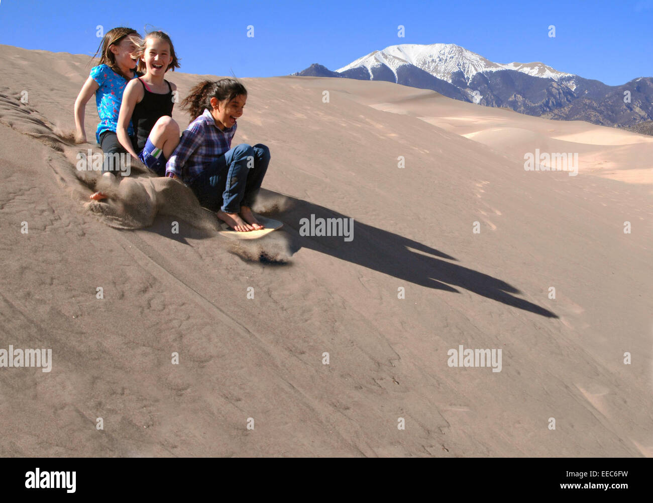 Children sand boarding ride down a dune above Medano Creek at the ...