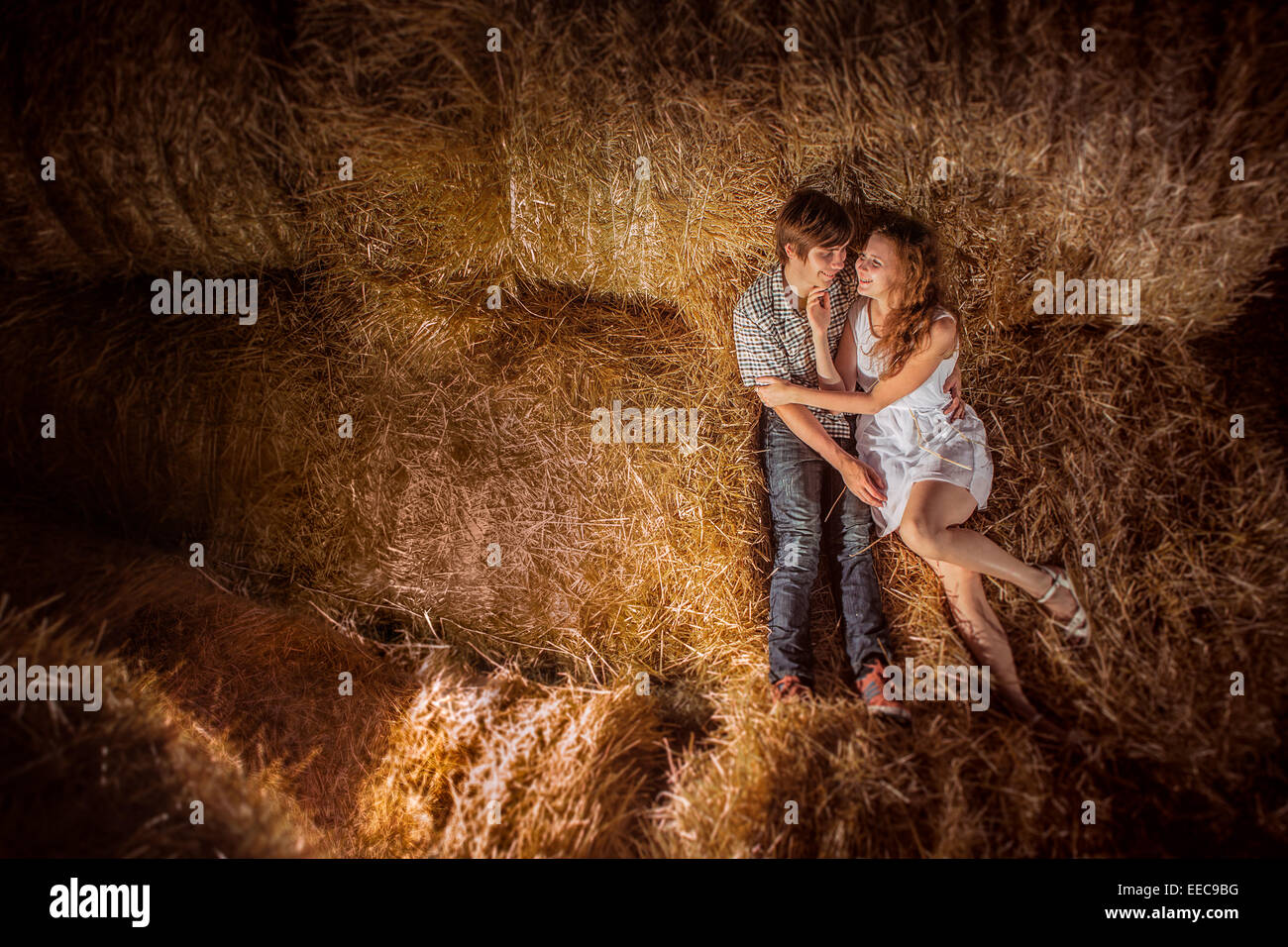 Young boy and girl lying in hay. Outdoor summer portrait of beautiful ...