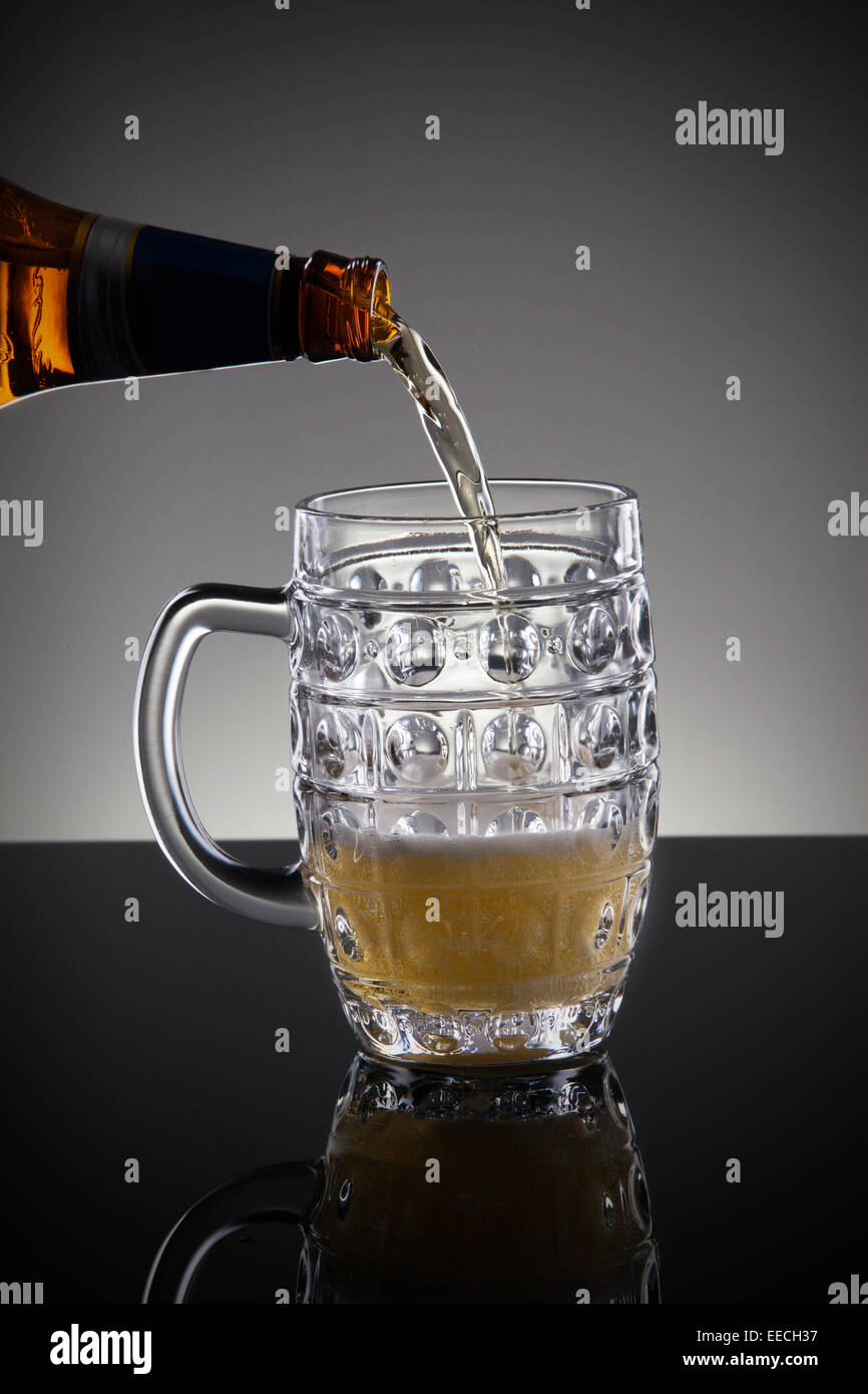 Pouring a beer into a beer mug on the dark background Stock Photo - Alamy