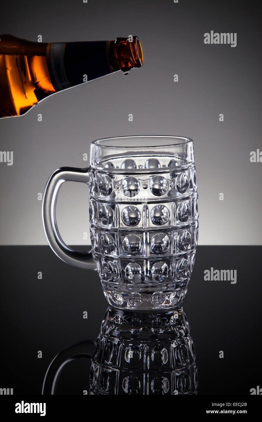 Pouring a beer into a beer mug on the dark background Stock Photo - Alamy