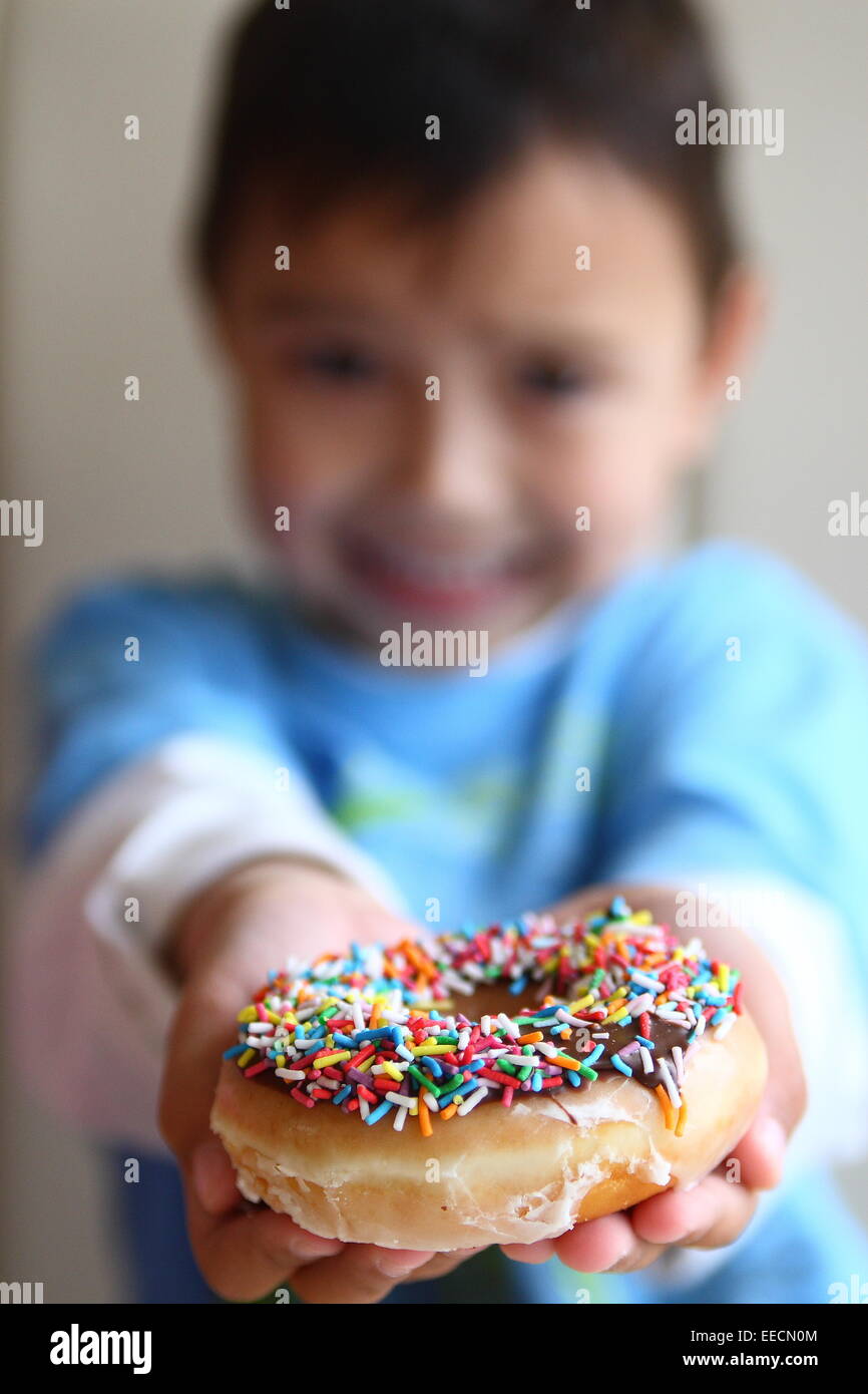 A child holding colorful sprinkle donut with donut in focus Stock Photo ...