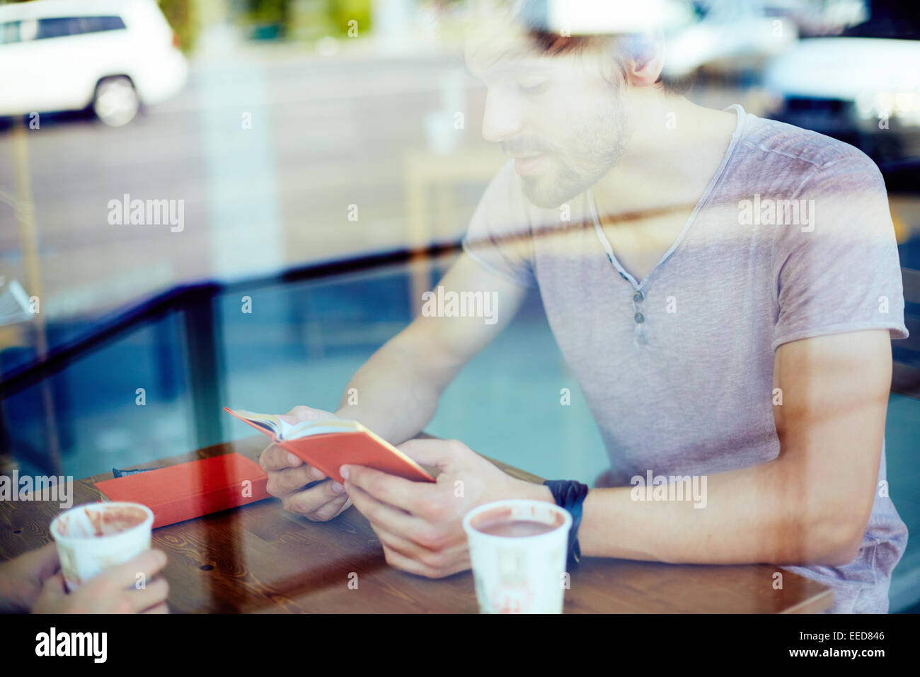 Young guy reading notes in notebook while sitting in cafe Stock Photo ...