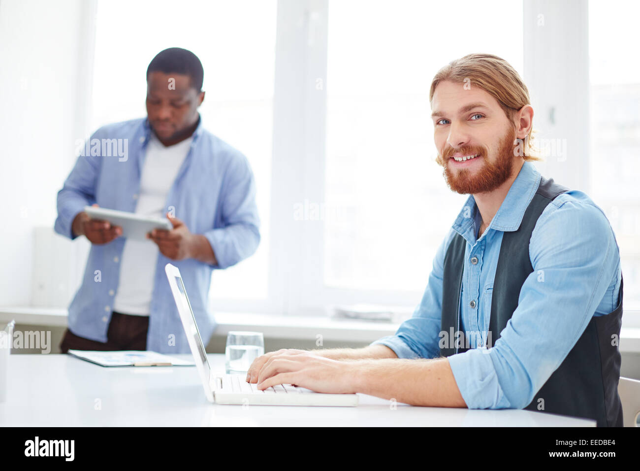 Successful manager computing at workplace with his colleague on ...