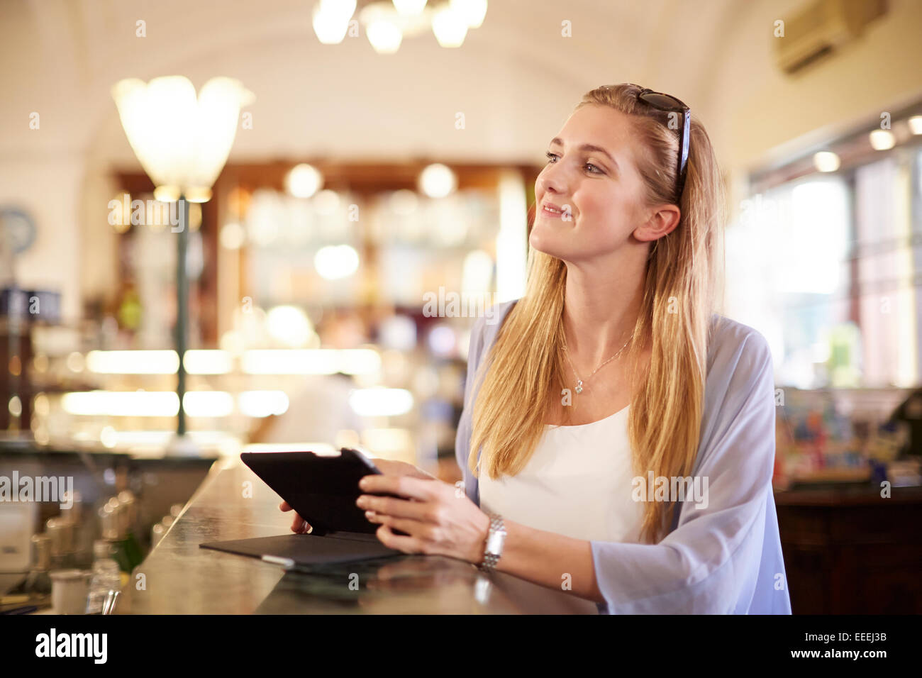 Woman at cafe drinking coffee reading her tablet Stock Photo - Alamy