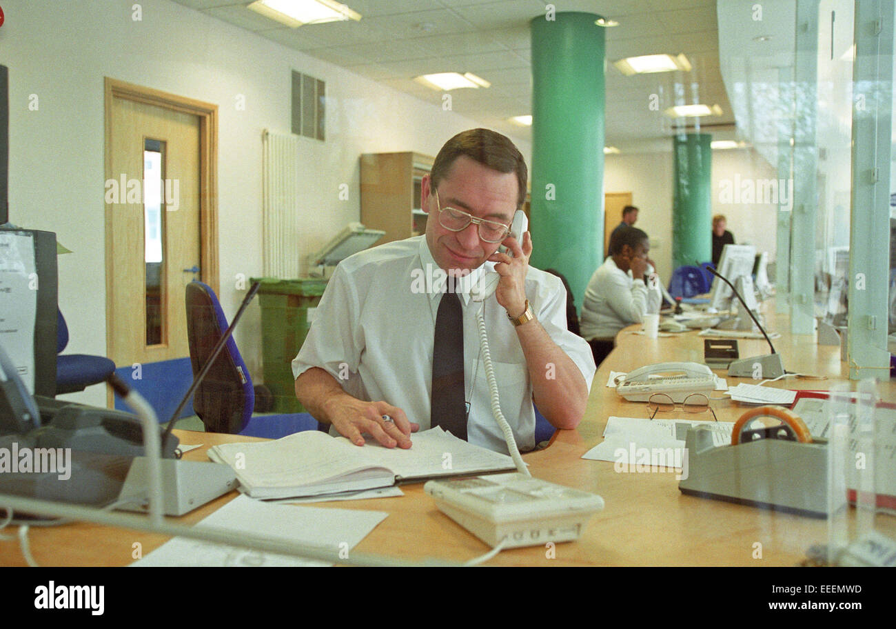Local authority employee behind a counter interviews an applicant by ...