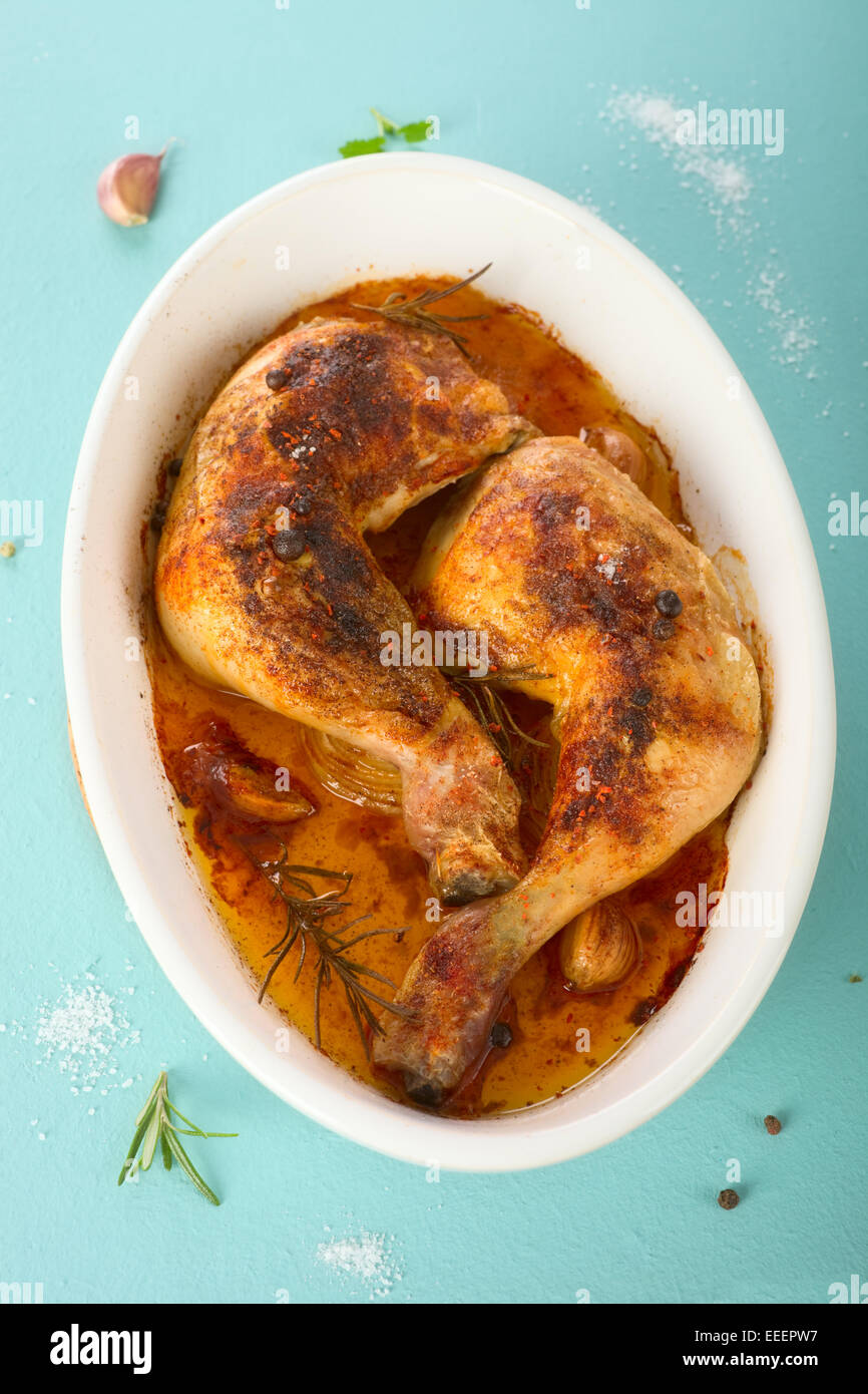 Two roasted chicken legs in a white baking dish Stock Photo - Alamy