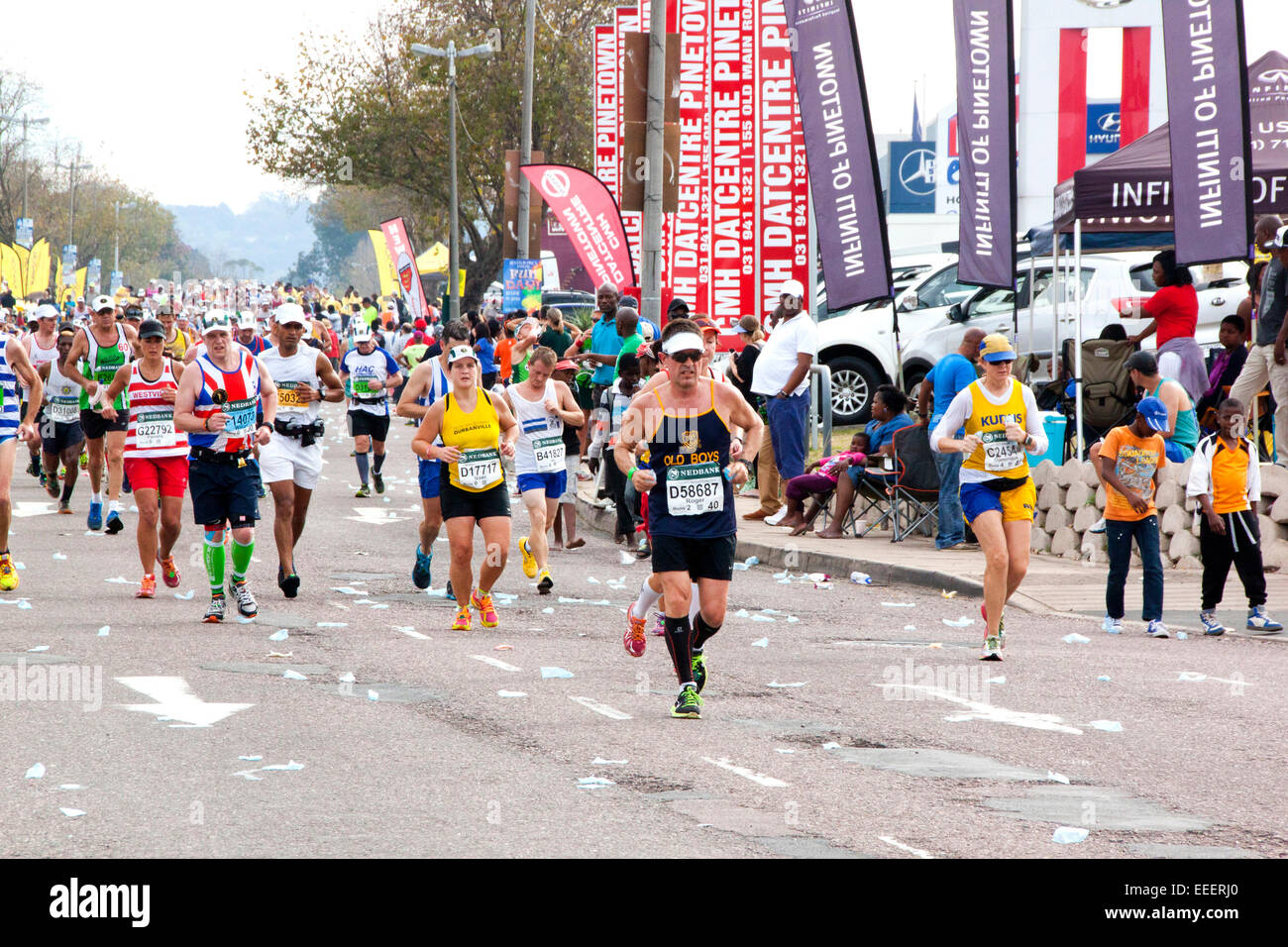 Spectators and runners competing in the long distance Comrades Marathon ...