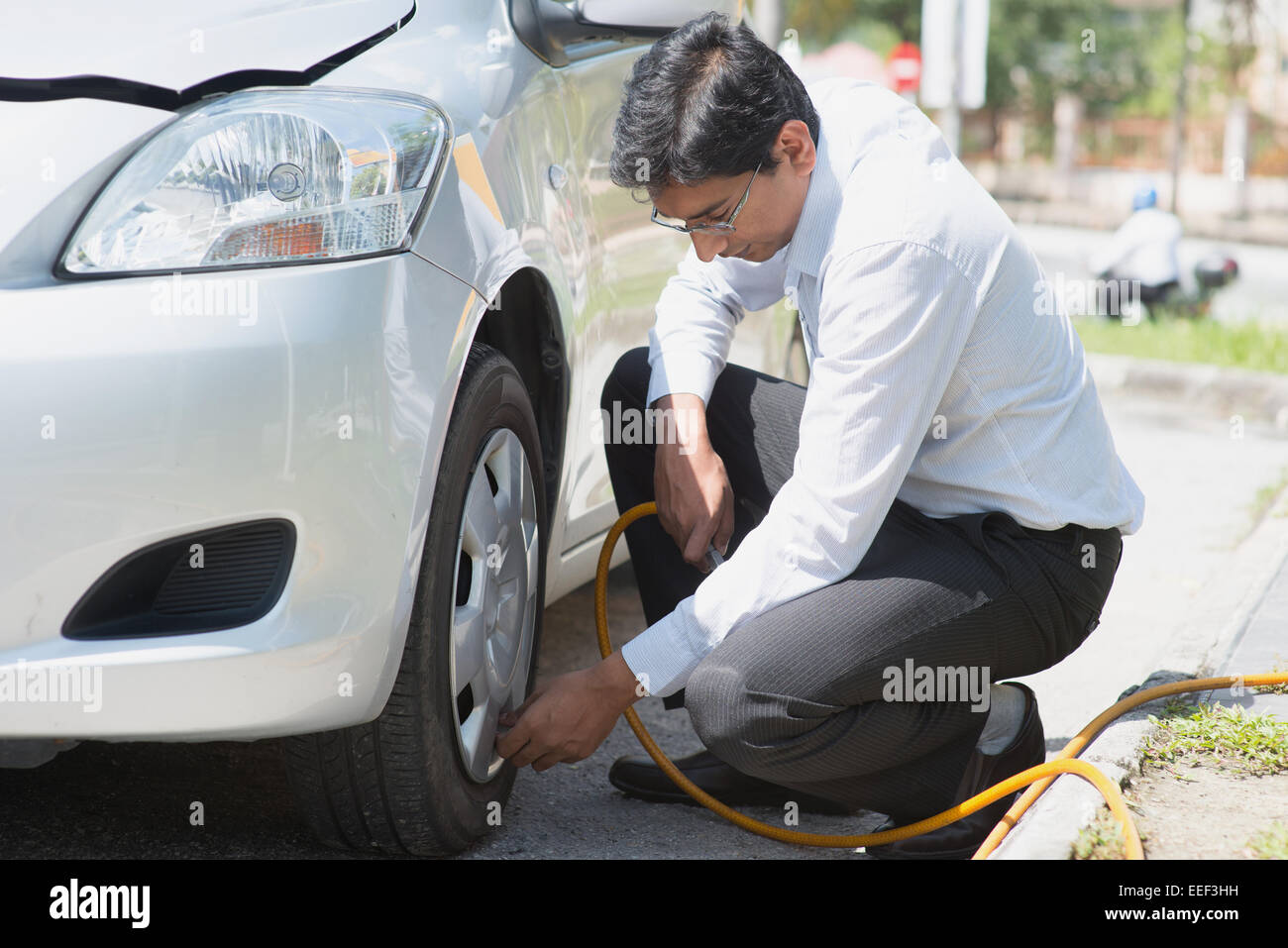 Indian driver checking air pressure and filling air in the tires of his ...