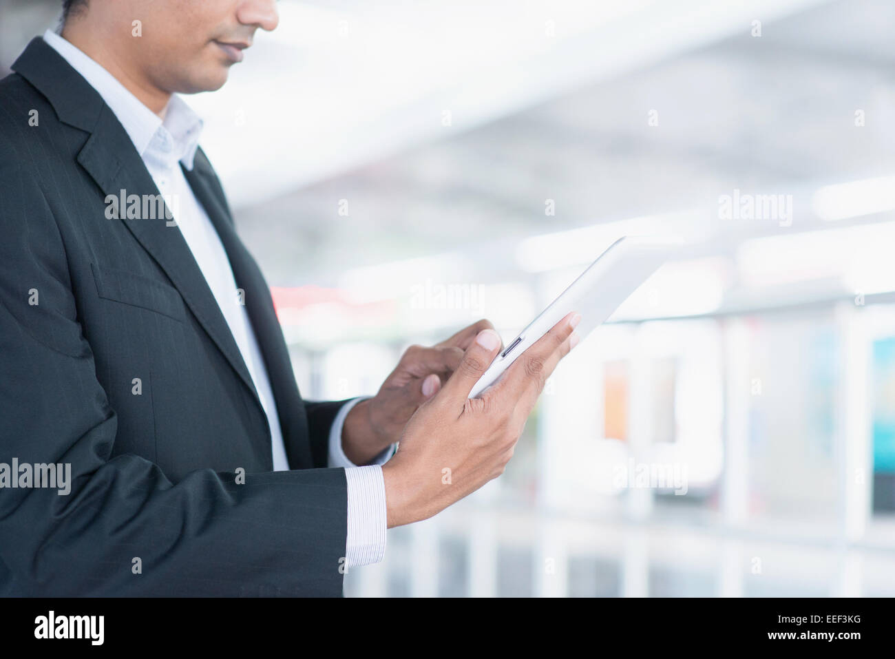 Asian Indian business people using tablet computer while waiting train ...