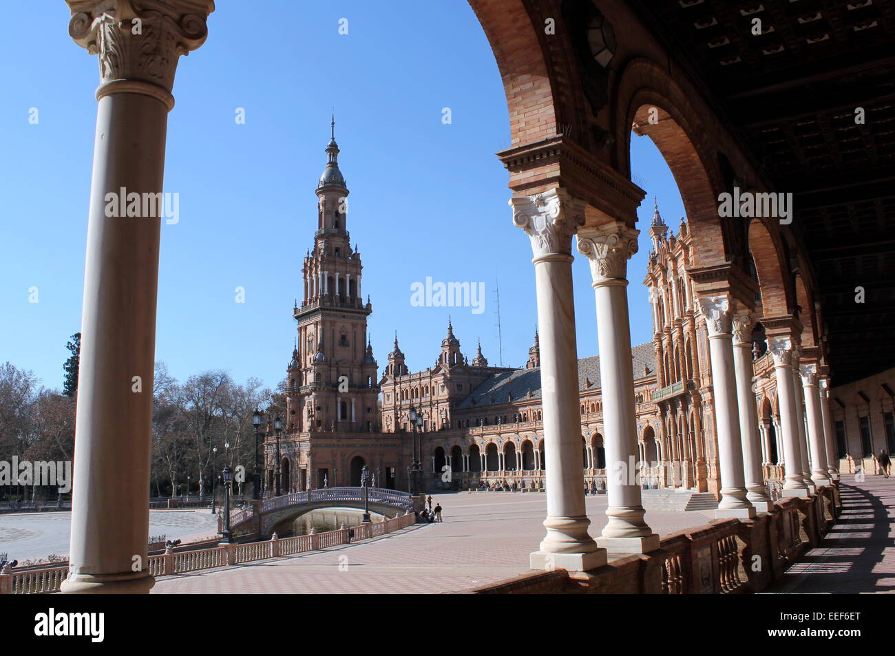 Colonnade with arch framing the tall south tower at Seville's Plaza de ...