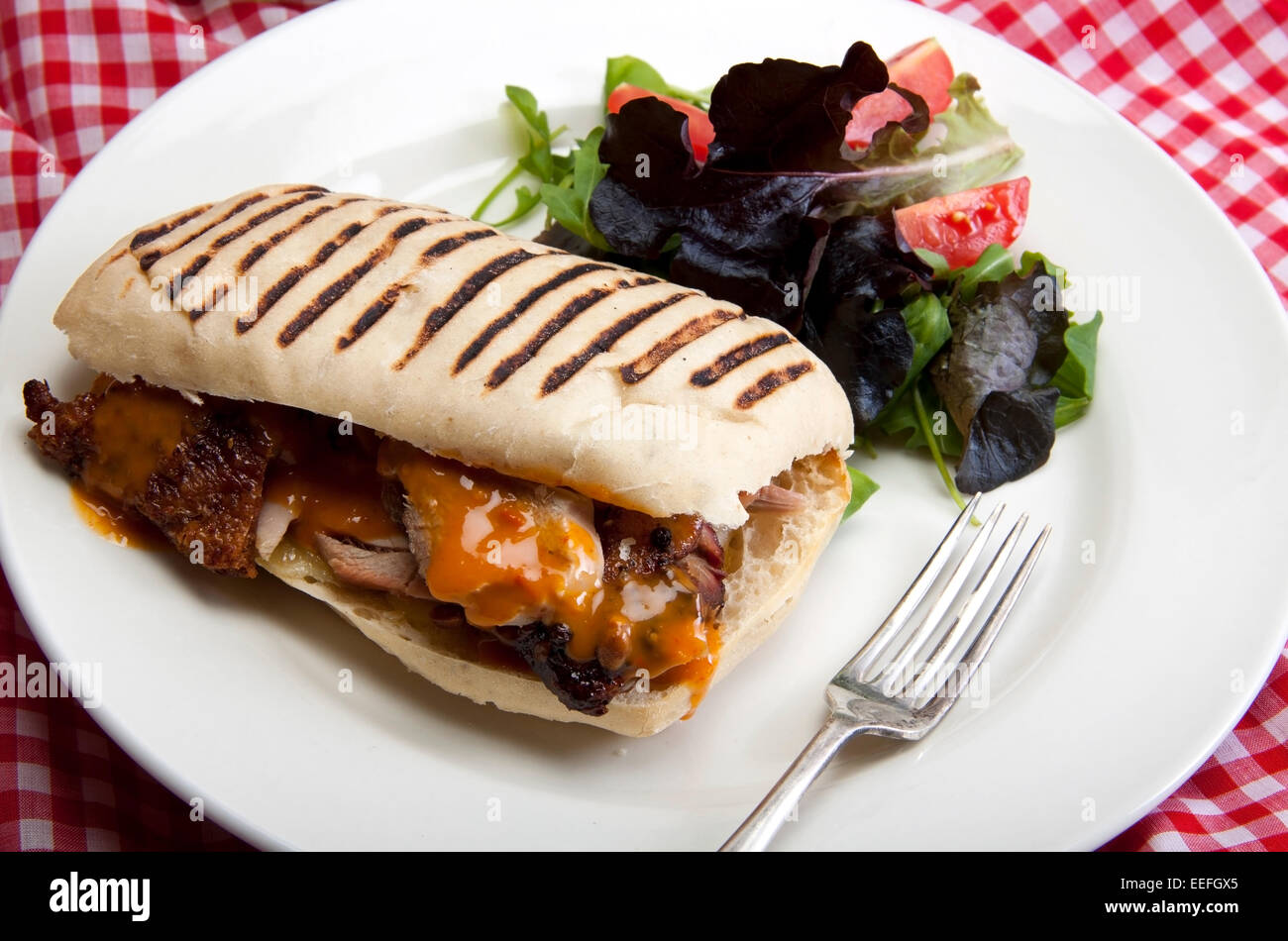 Home made panini with egg and bacon on a small white plate, ready to be ...