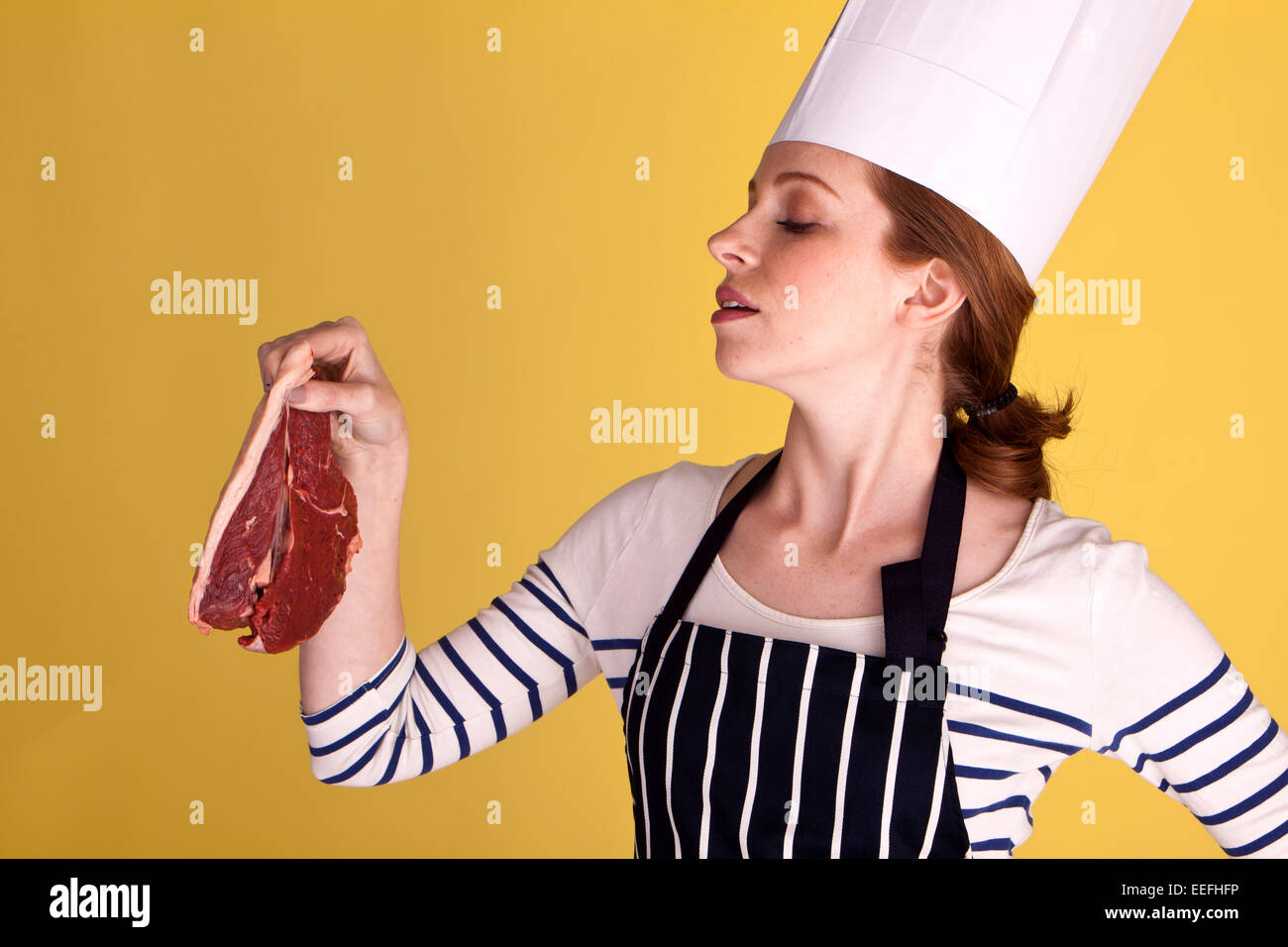 A young and attractive female chef holding a nice piece of steak ready ...