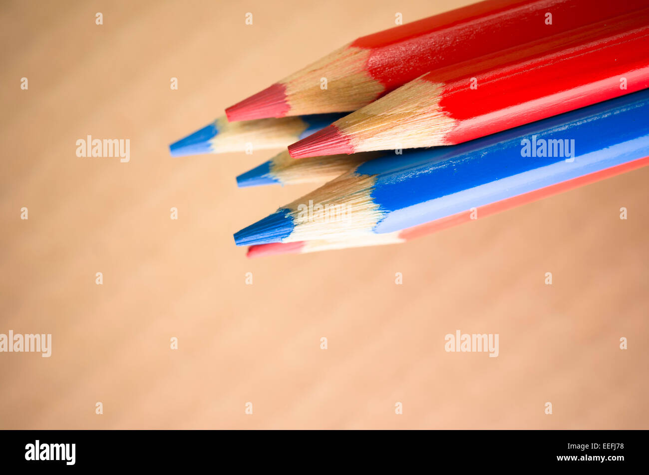 red blue colored wood crayons close up on a blurred light paperboard ...