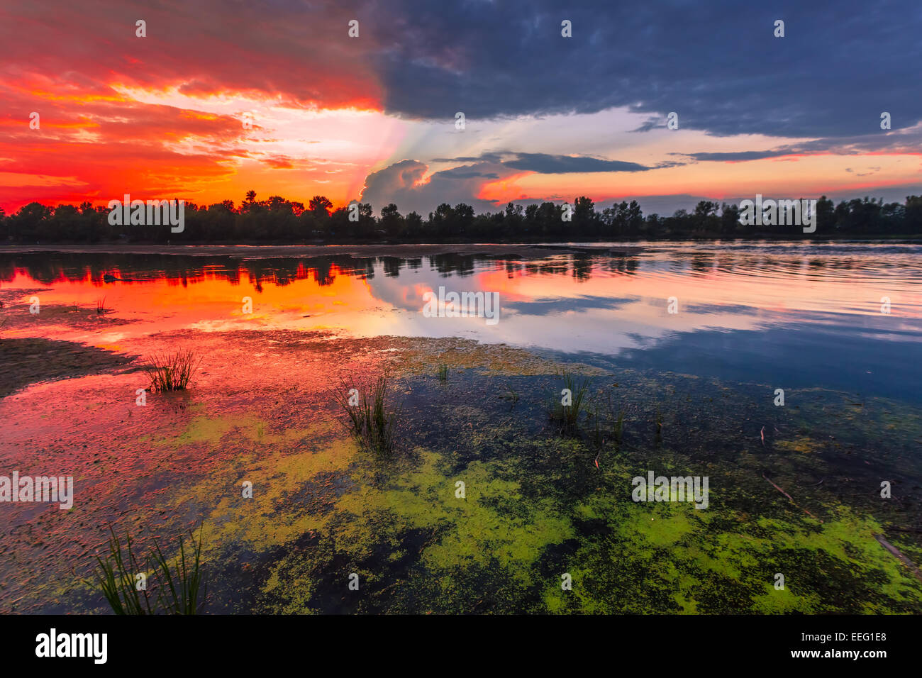 Amazingly colorful sunset with reflective red sand and bright clouds ...