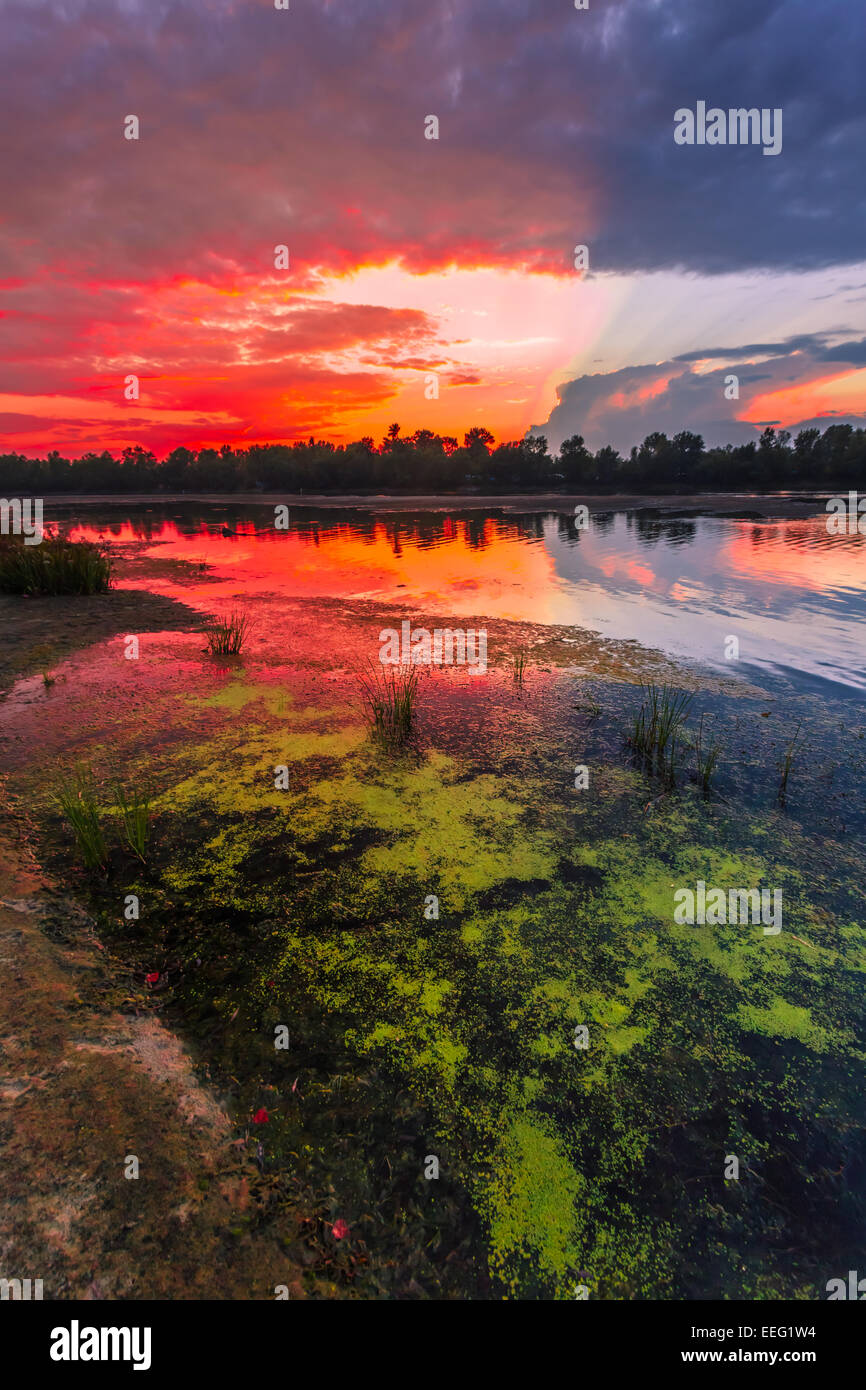 Amazingly colorful sunset with reflective red sand and bright clouds ...