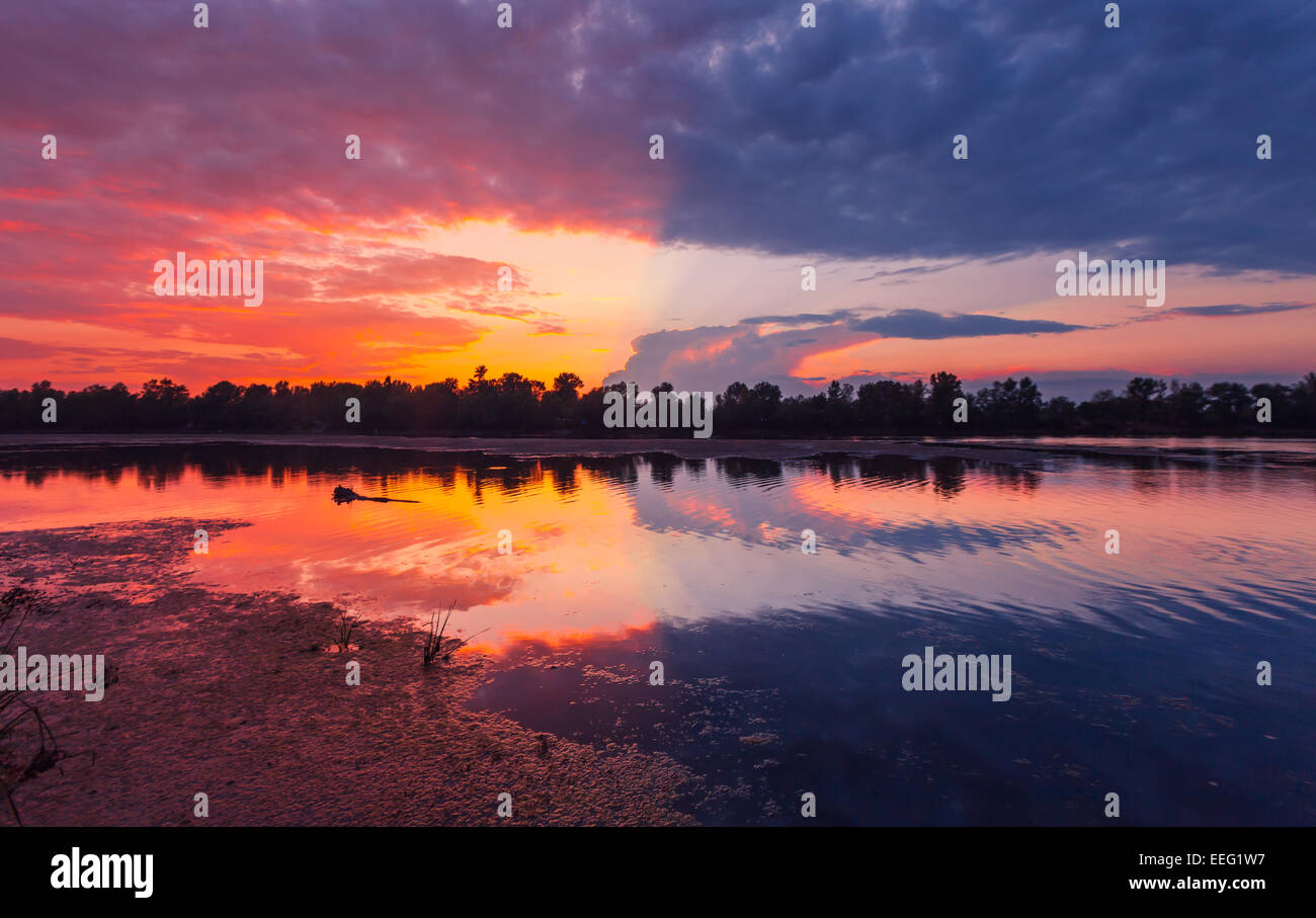 Amazingly colorful sunset with reflective red sand and bright clouds ...