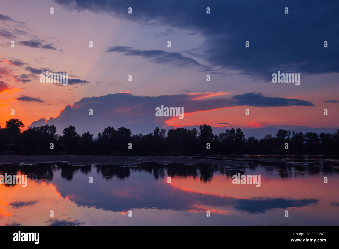 Amazingly colorful sunset with reflective red sand and bright clouds ...