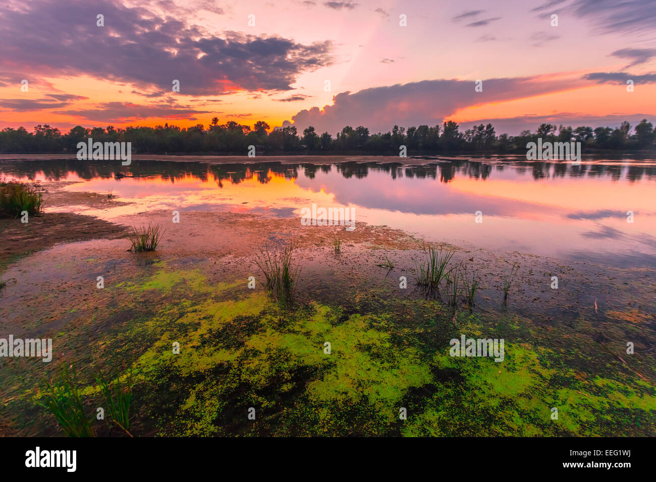 Amazingly colorful sunset with reflective red sand and bright clouds ...