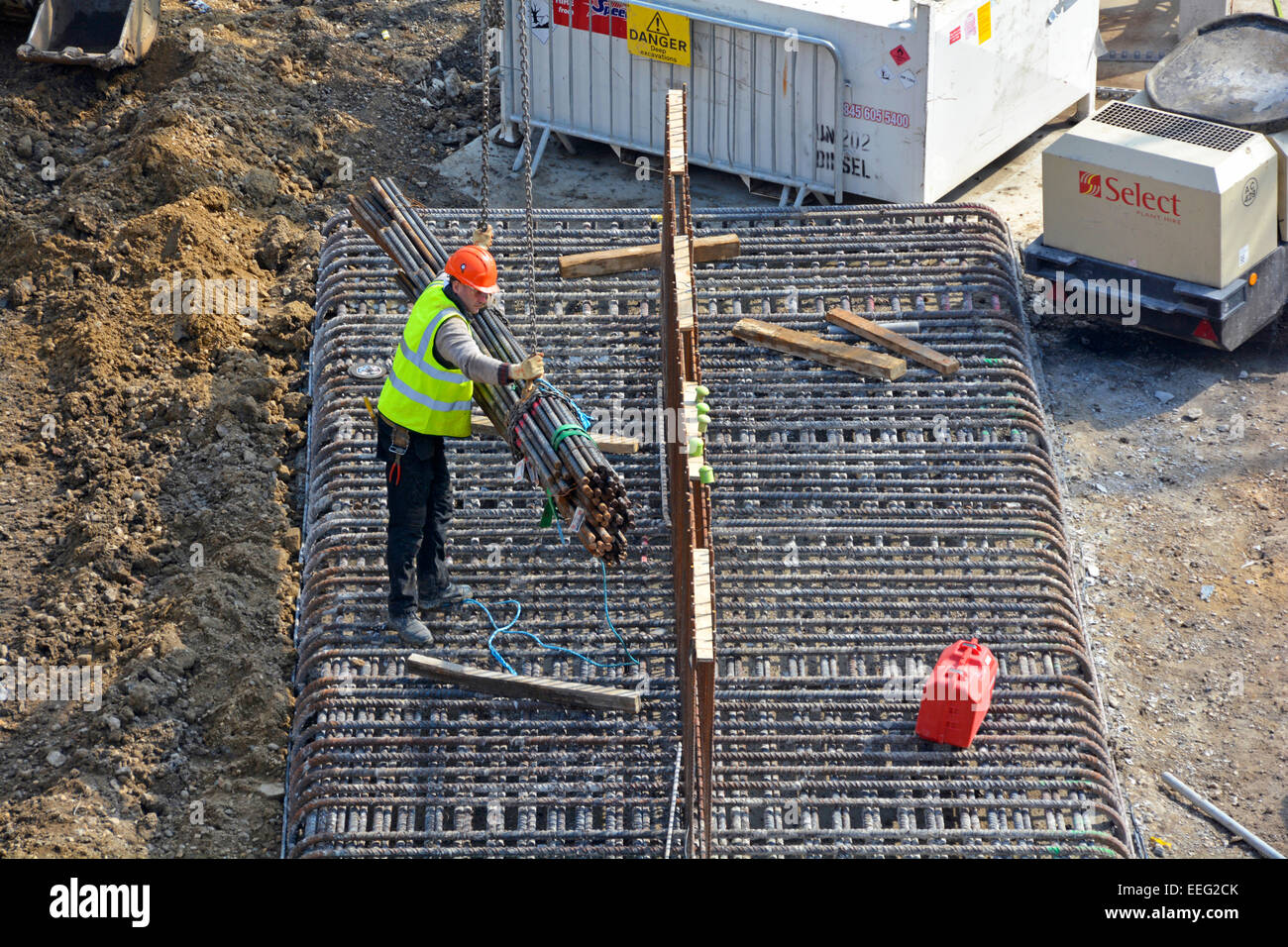 Steel fixer worker guiding a crane lowering bundle of reinforcing rods ...