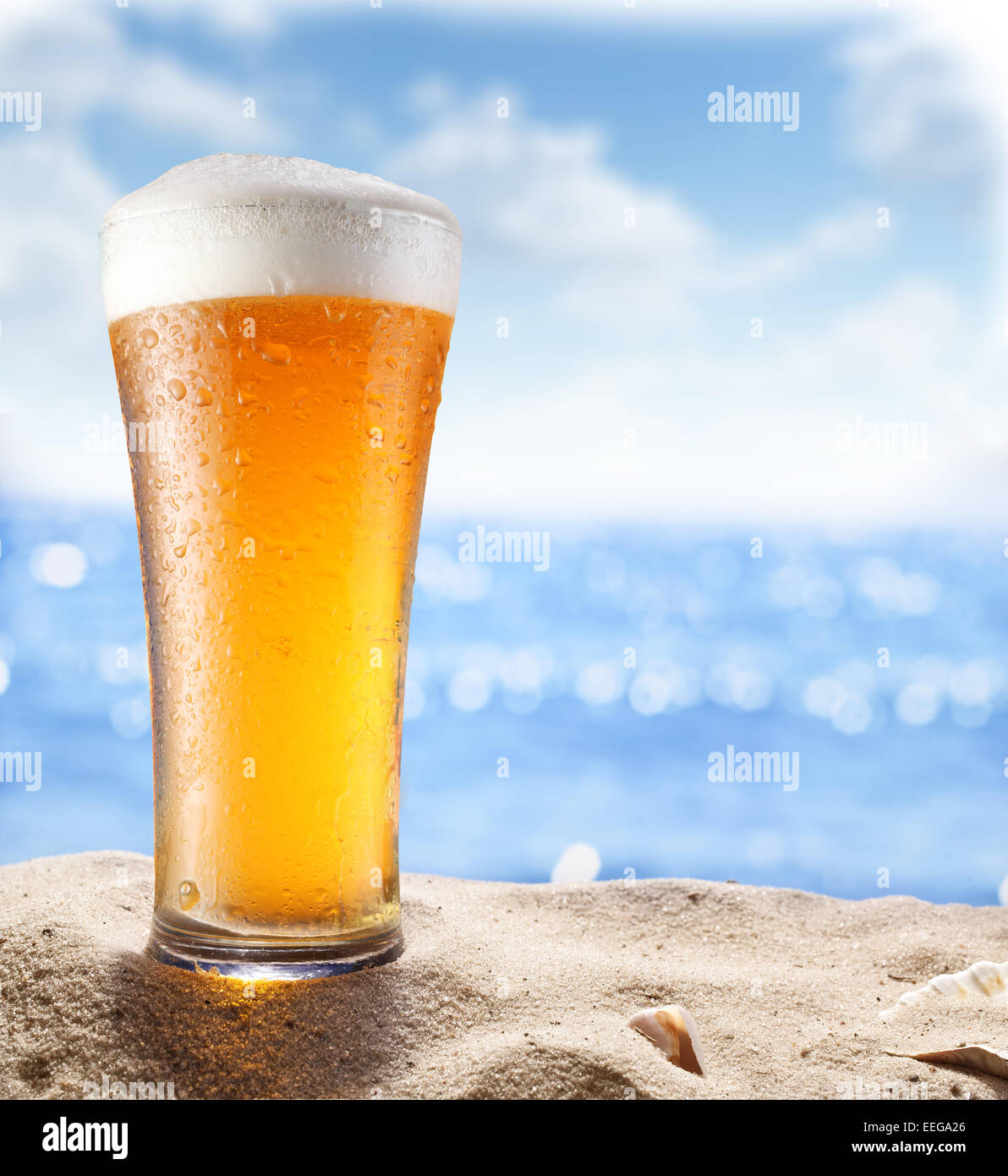 Ice beer glass in the sand. Blurred sea at the background Stock Photo ...