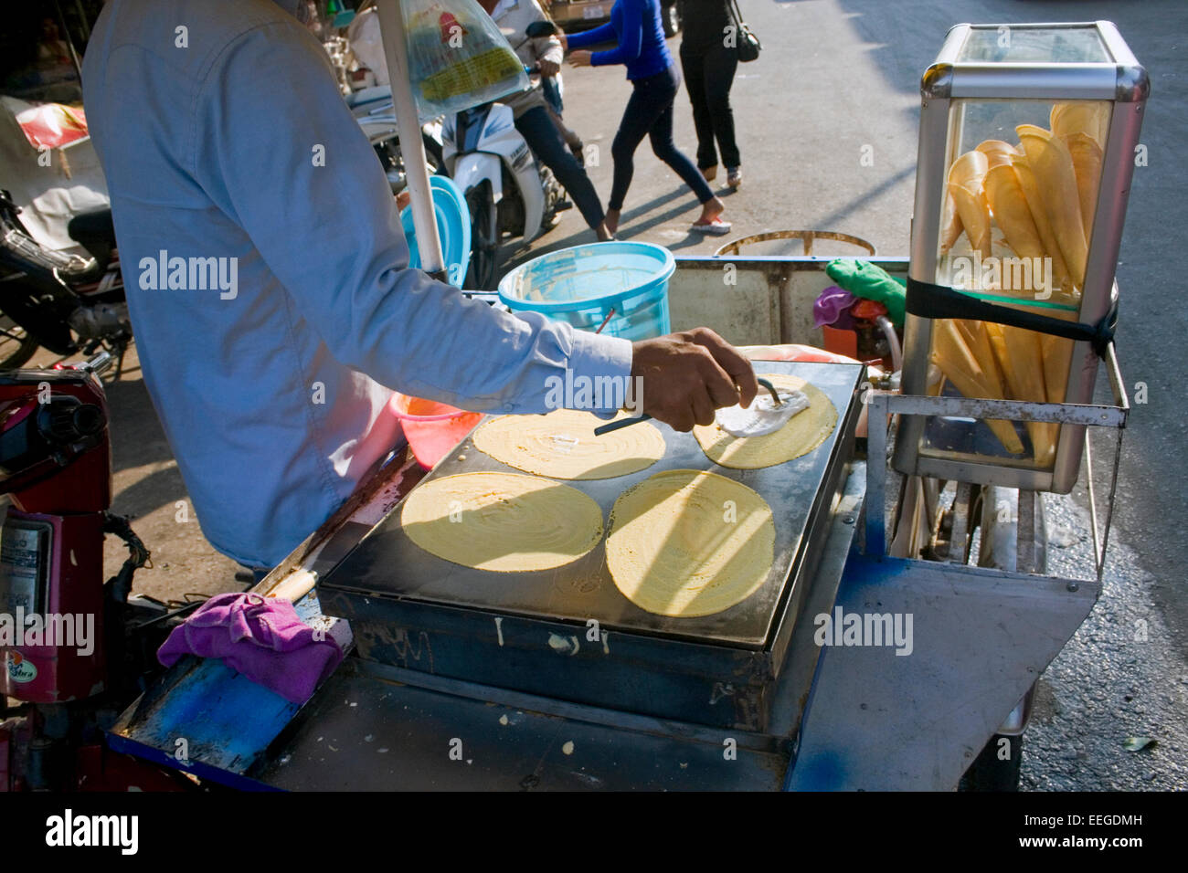 A man is making roti, a popular street food in southeast Asia, on a ...