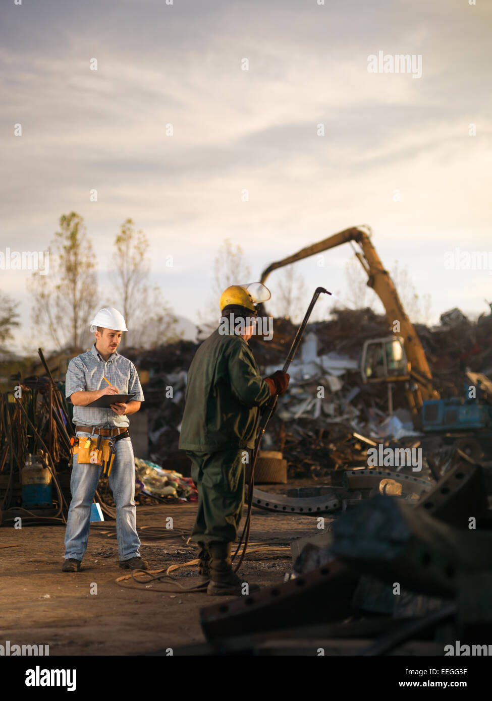 caucasian engineer standing at scrap metal recycling site, inspecting ...