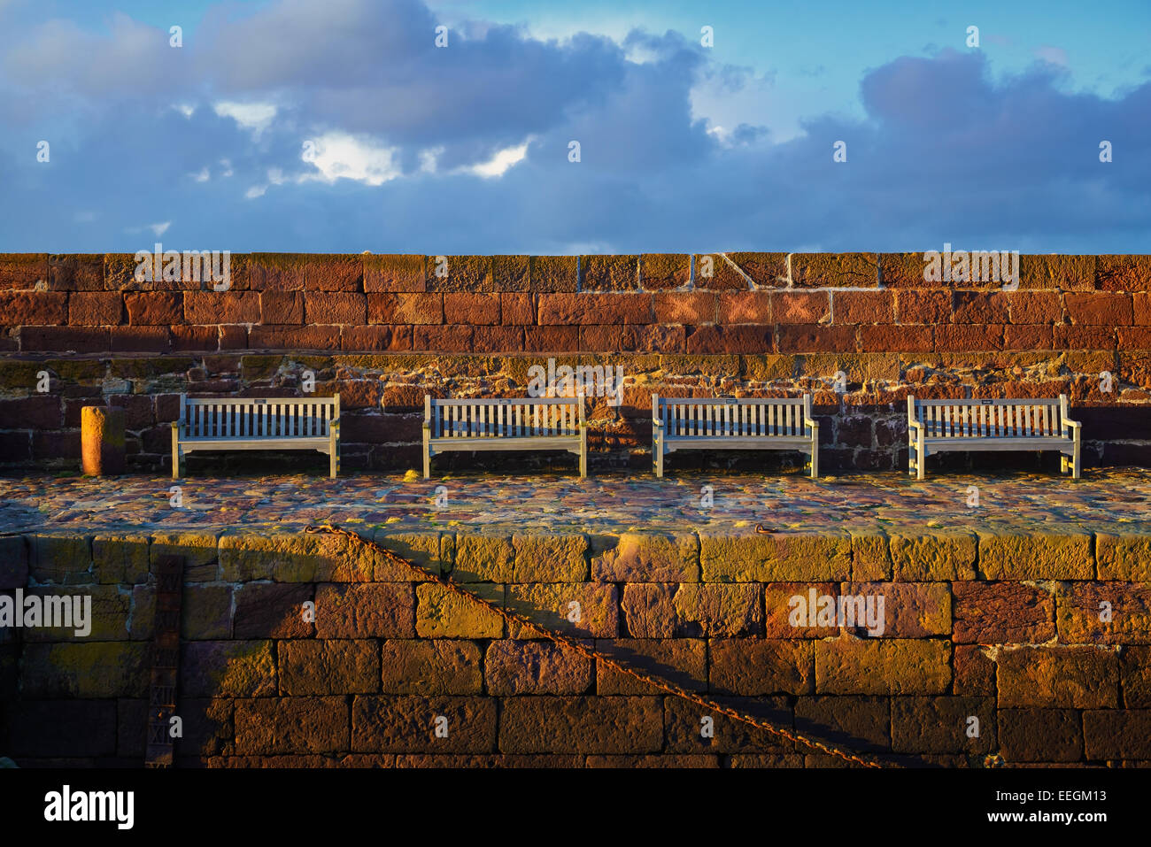 Wooden benches on a red stone harbour wall. North Berwick, East Lothian ...