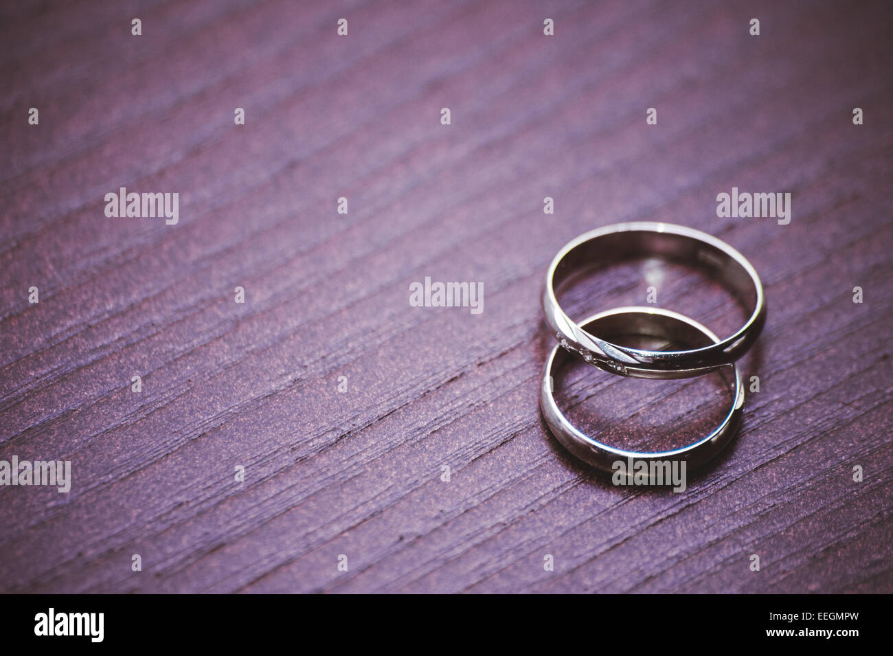 two wedding rings laying on wooden table Stock Photo - Alamy