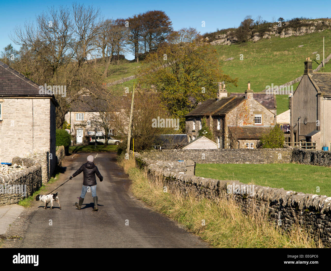 UK, Derbyshire, Tideswell, Litton village, dog walker on road below ...
