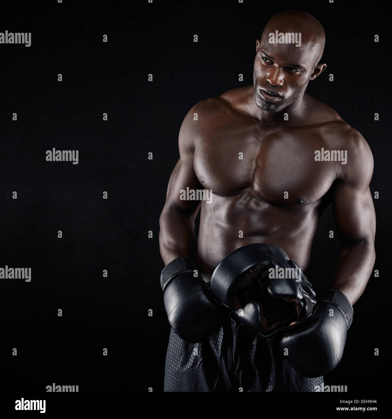 Portrait of sporty young man with muscular body holding boxing helmet ...