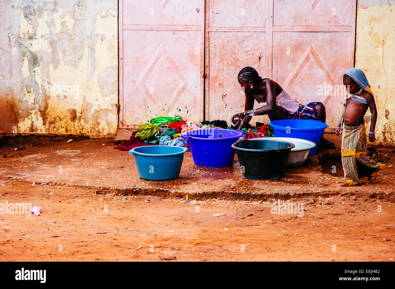 A woman and her daughter washing clothes in the street, Senegal Stock ...
