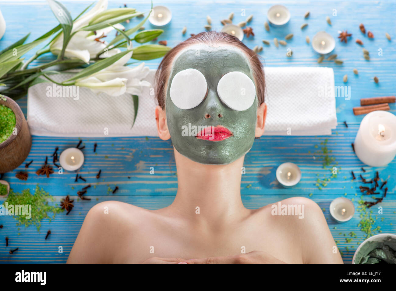 Young woman with spa facial mask on her face and cotton tampons on her ...