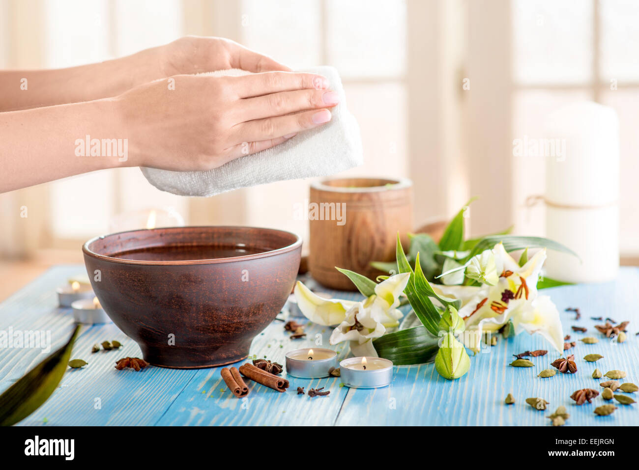 Drying hands with bath towel on wooden table with spa stuff on ...