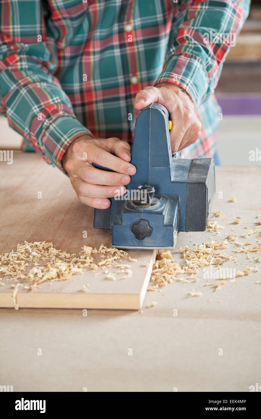 Carpenter Using Electric Planer On Plank Stock Photo - Alamy