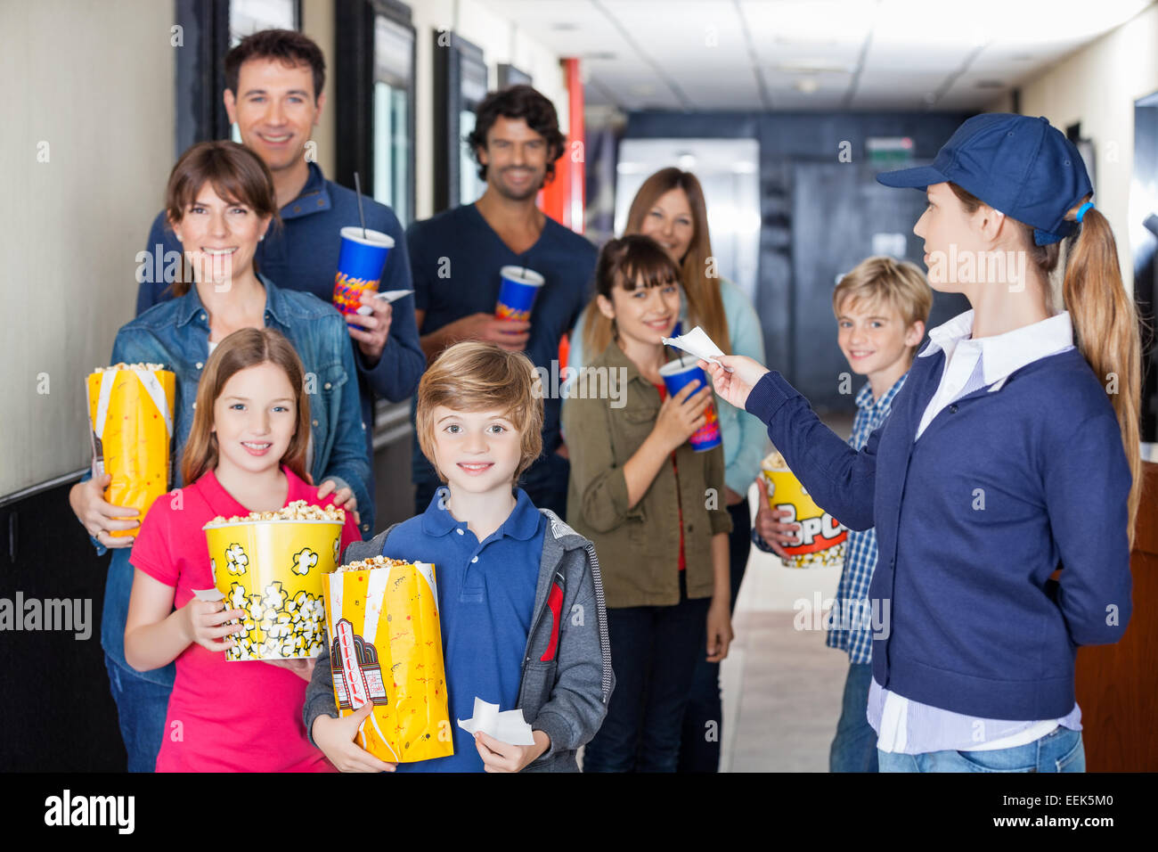 Worker Giving Tickets To Families At Cinema Stock Photo - Alamy